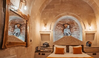 Quarto com cama, duas mesas de cabeceira, espelho e luminária na parede.