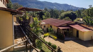 Uma casa com telhado vermelho, chaminé de pedra e jardim com diversas plantas.