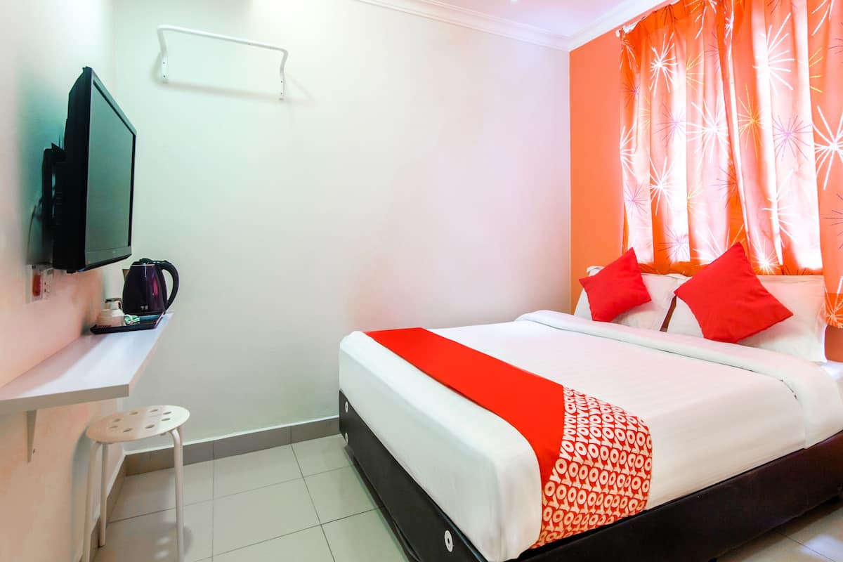 Quarto de hotel com cama, secretária com televisão e máquina de café.