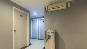 Corredor com bebedouro, unidade de ar condicionado e duas portas numeradas.