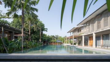 Piscina cercada por plantas tropicais e edifícios modernos.