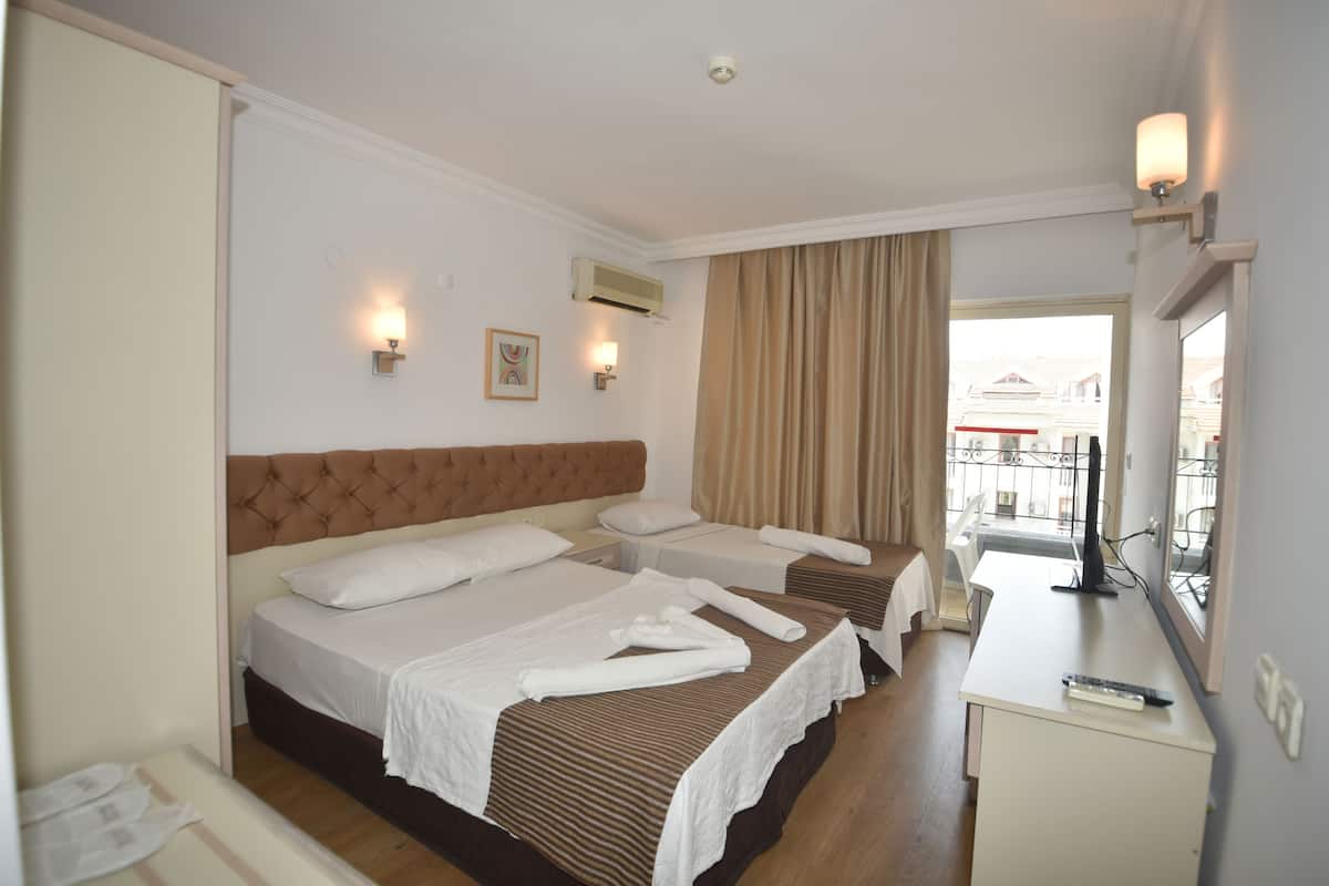 Quarto de hotel com duas camas, uma escrivaninha e uma janela com cortinas.