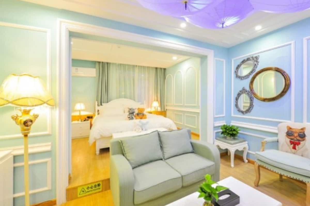 Quarto de hotel com cama, sofá, poltrona e mesa pequena.