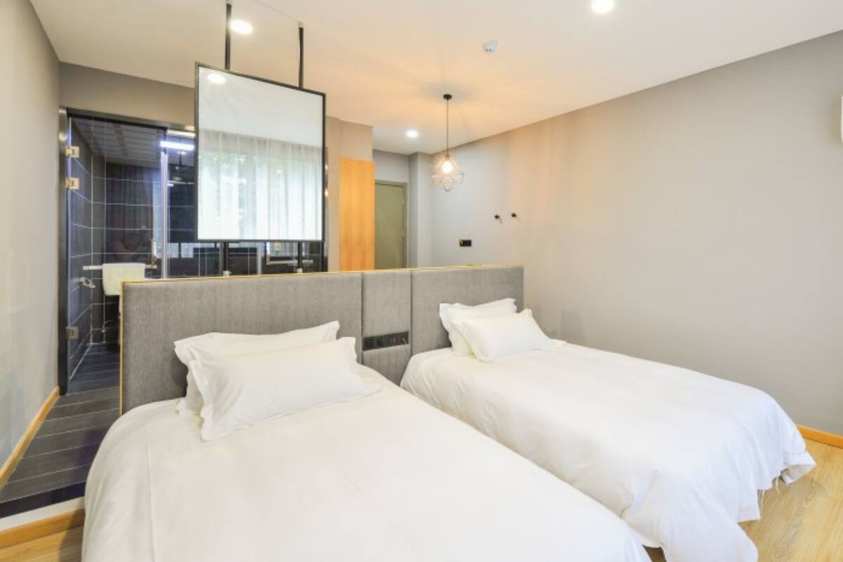 Quarto de hotel com duas camas, um espelho grande e vista para um banheiro.