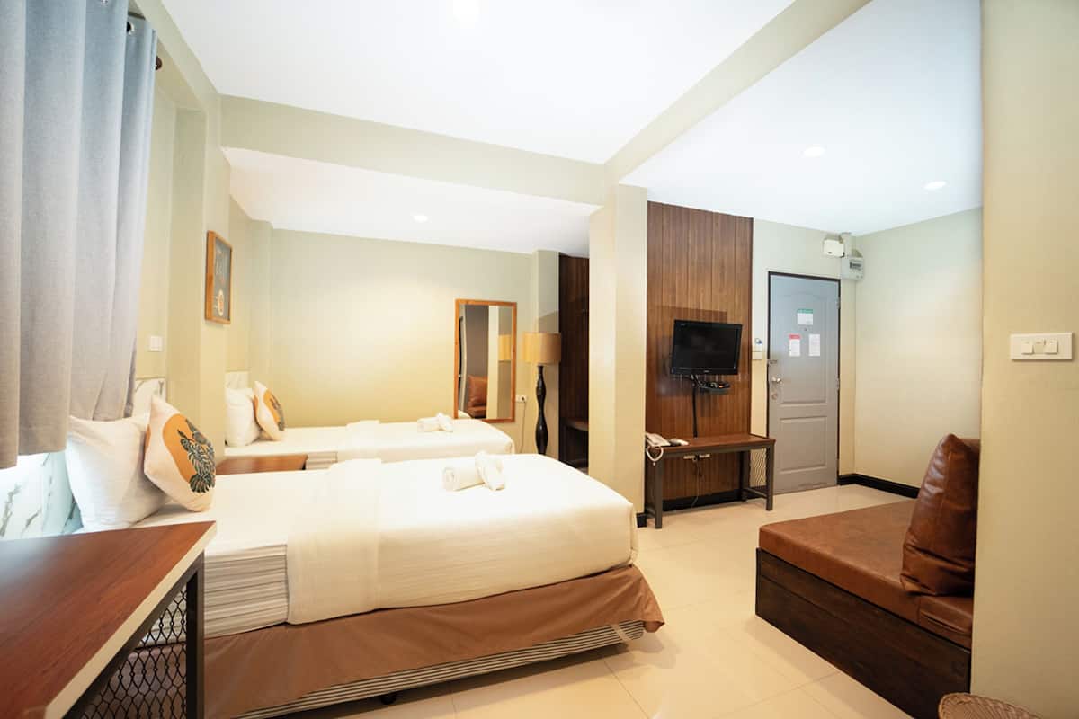 Quarto de hotel com duas camas, um sofá, uma televisão e uma mesa.