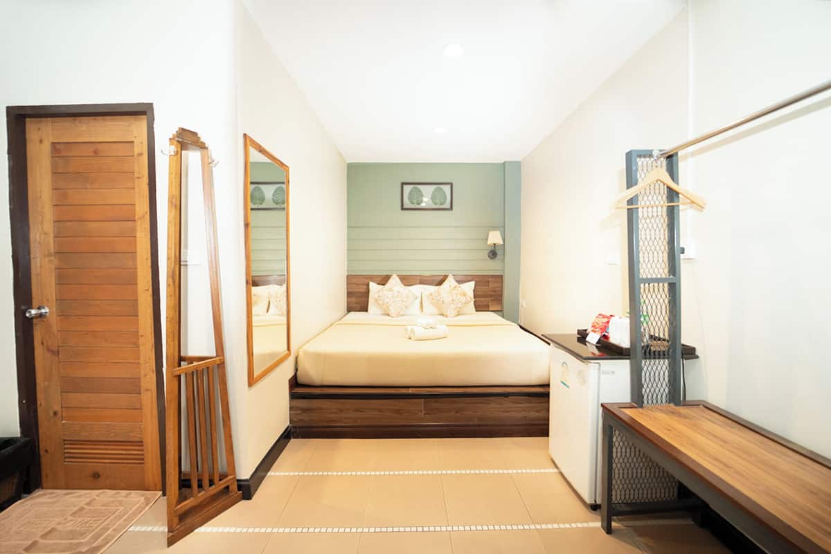 Quarto compacto com cama, mesa de cabeceira e guarda-roupa.