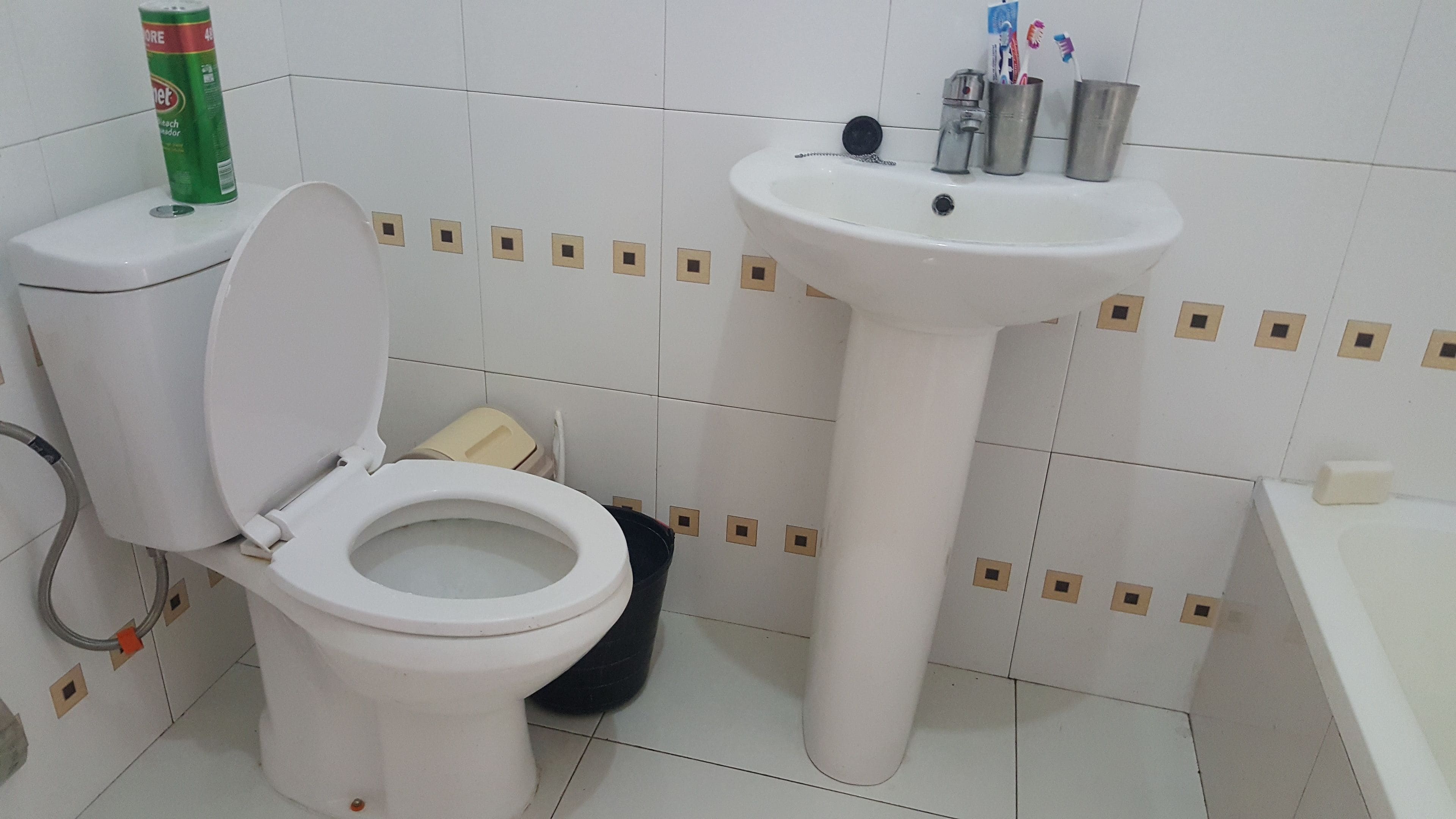 Um banheiro com vaso sanitário, pia e lixeira.