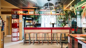 Uma área de bar com bancos, balcão e prateleiras com garrafas e plantas.
