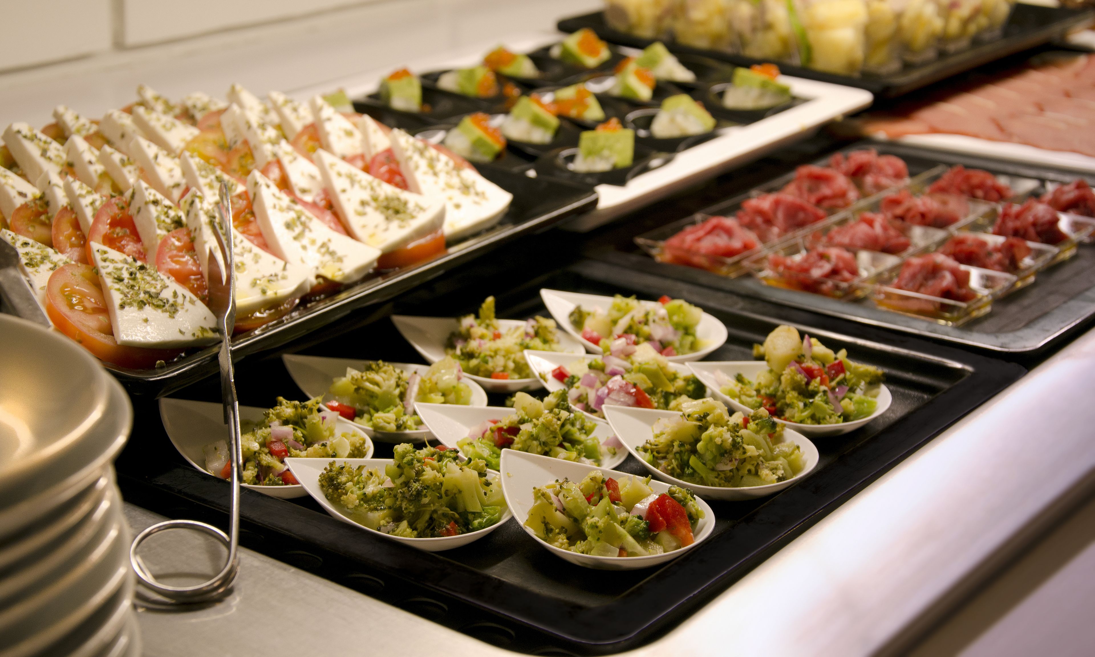 Buffet com diversas opções de comida, incluindo saladas, carnes e queijos.
