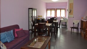 Sala de estar com sofá, mesa de centro e área de jantar com cadeiras e mesa.