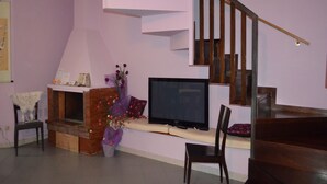 Uma sala de estar com lareira, televisão, uma cadeira e escada.