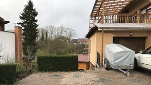 Uma entrada residencial com carro coberto, garagem e estrutura de pérgola de madeira.