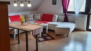 Uma sala de estar acolhedora, com um sofá, uma mesa de jantar e um lustre.