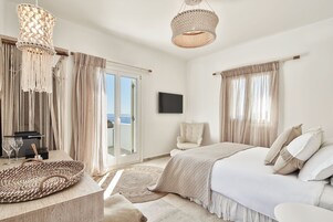 Quarto com uma cama, uma cadeira, uma televisão e vista para o exterior.
