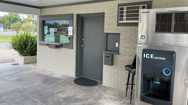Edifício comercial com fachada de tijolos, câmera de segurança e dispensador de gelo.