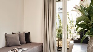 Uma sala de estar moderna com um sofá, uma revista e vista para o exterior através de uma porta de vidro.