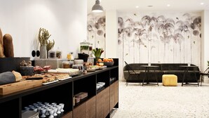 Uma cozinha moderna com bancada de madeira, área de jantar com sofá e cadeiras, e parede decorativa com arte abstrata.