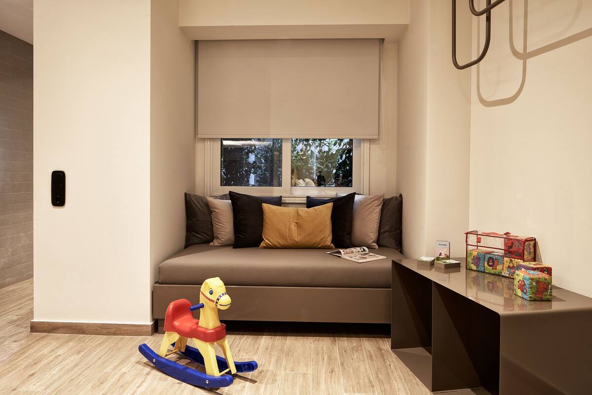 Uma sala de estar moderna com um sofá, um cavalinho de balanço e uma mesa com objetos sobre ela.