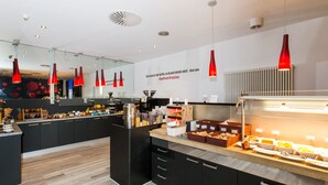 Cozinha moderna com armários pretos, bancadas de madeira e luminárias pendentes vermelhas.