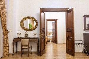 Quarto com escrivaninha de madeira, uma cadeira, um espelho e porta que dá para outro aposento.