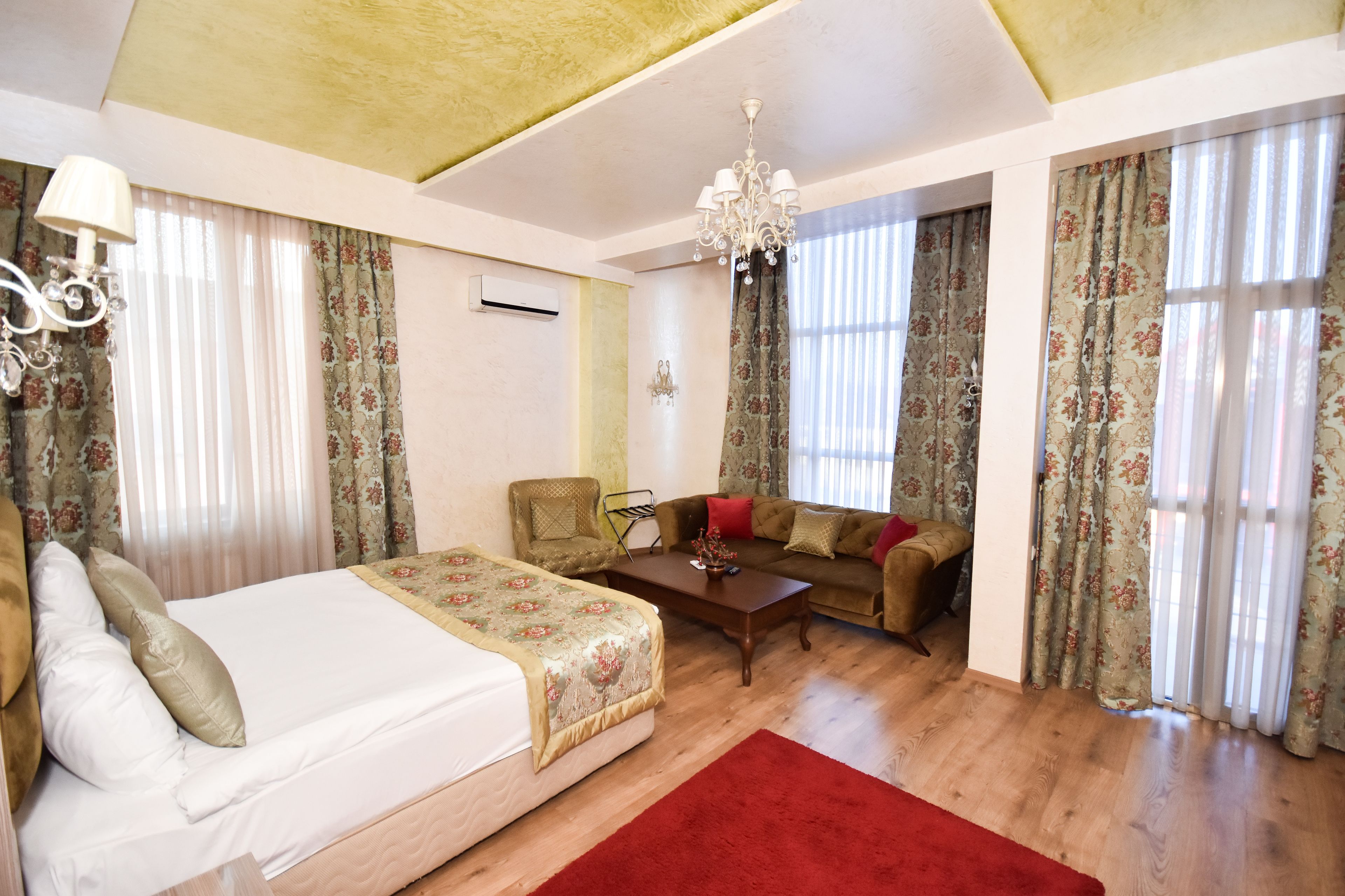 Quarto de hotel com uma cama, um sofá, uma mesa de centro e um candelabro.