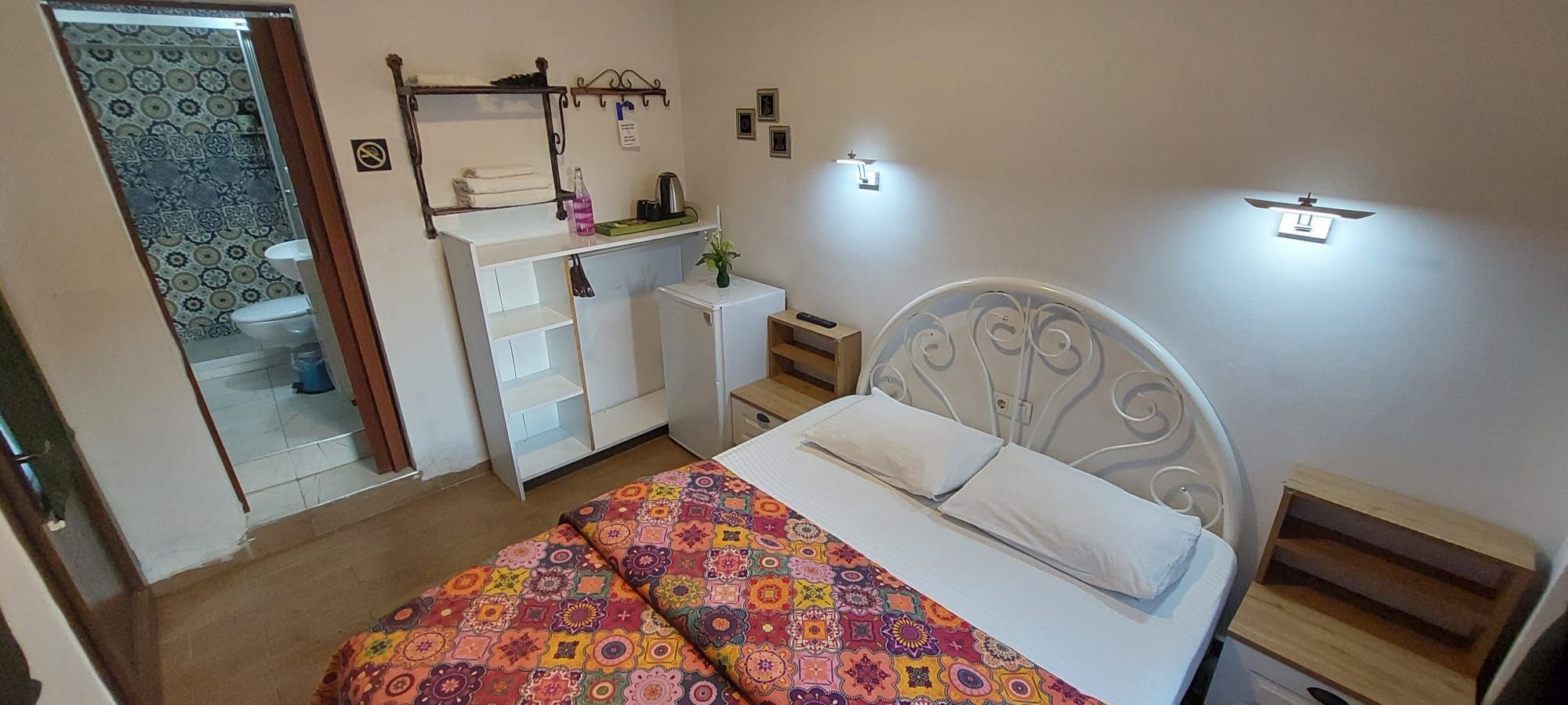 Quarto com cama, cômoda, mesa de cabeceira, espelho e luminária.