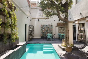Um pátio com piscina, área de estar externa, plantas em vasos e luzes de Natal.