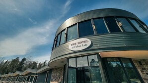 Um hotel com fachada curva, grandes janelas e uma placa indicando o nome e a localização.