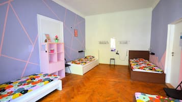 Quarto com duas camas, uma estante rosa e uma mesa pequena.