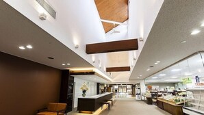 Um lobby de hotel moderno com assentos, balcão de recepção e área de exposição de alimentos.