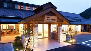 Um hotel com estilo arquitetônico japonês tradicional, apresentando entrada de madeira e pilares de pedra.