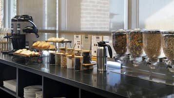 Uma mesa de buffet com diversos alimentos e uma máquina de café.
