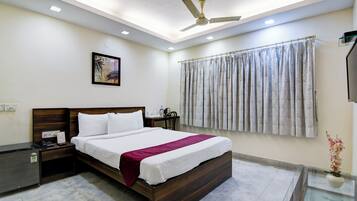 Quarto de hotel com cama, mesa de cabeceira e ventilador de teto.