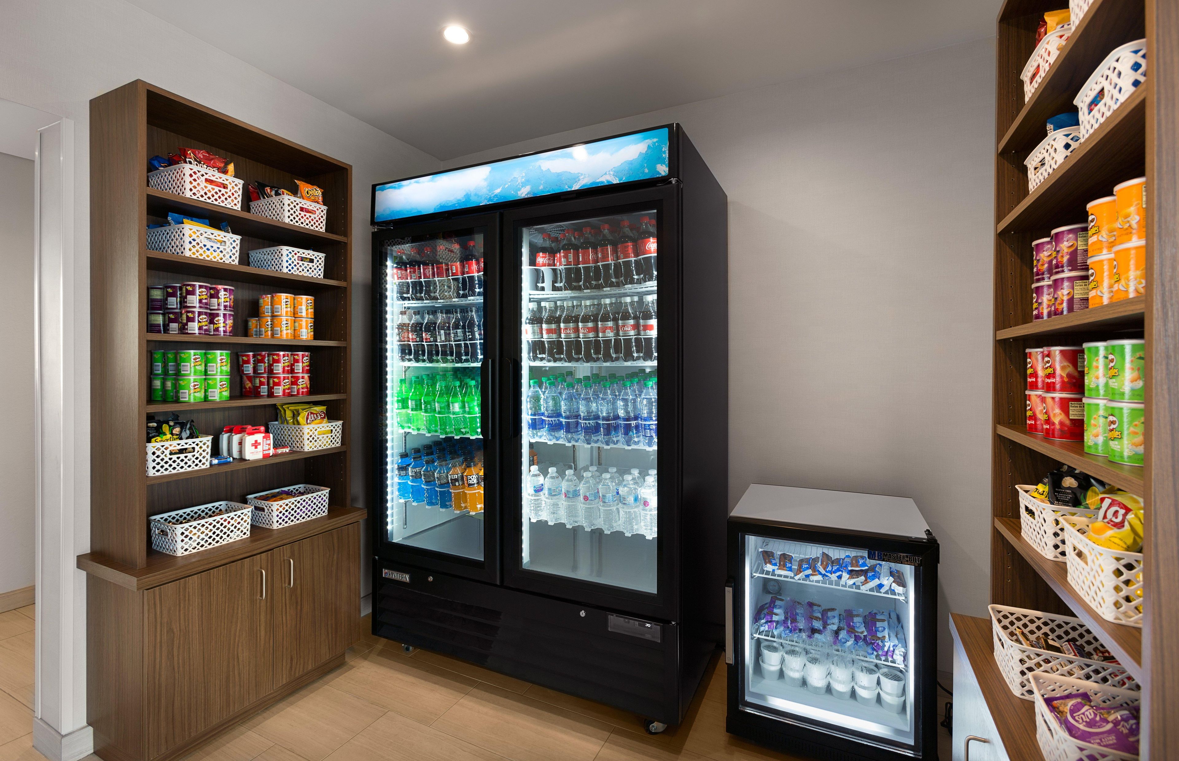 Uma área de máquinas de venda automática com dois distribuidores de bebidas e prateleiras repletas de lanches e bebidas.