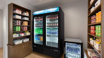 Uma área de máquinas de venda automática com dois distribuidores de bebidas e prateleiras repletas de lanches e bebidas.