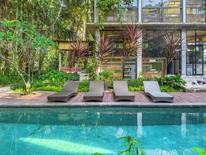 Uma área de piscina com espreguiçadeiras e um edifício com varanda.