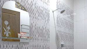 Casa de banho com lavatório, espelho, chuveiro e azulejos estampados.