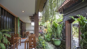Um jardim interno com móveis de madeira e plantas em vasos.