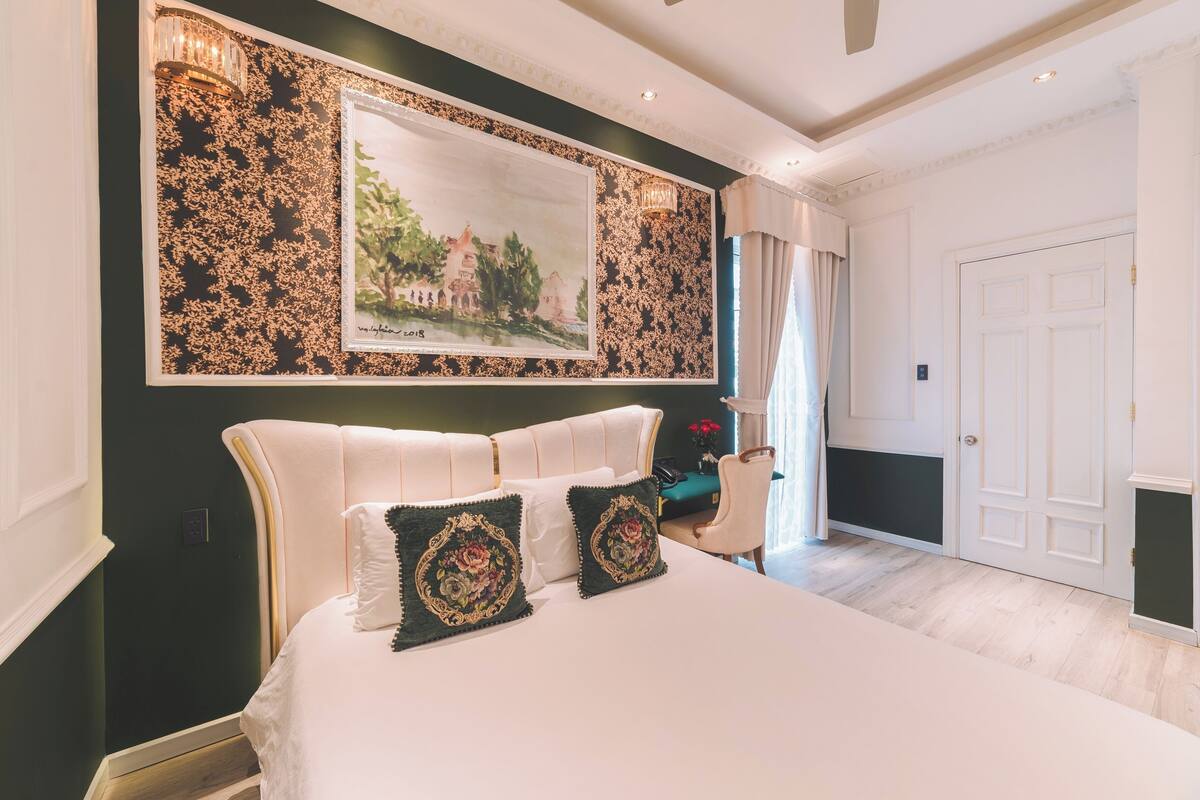 Quarto com uma cama grande, um quadro de paisagem e um candelabro.