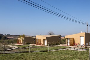 Uma fileira de edifícios modernos, térreos, com telhado plano, uma pequena área de pátio e uma bicicleta estacionada na frente.