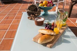 Uma mesa posta para o café da manhã, com pão, frutas e suco.