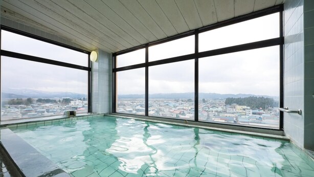 Uma piscina interior ampla com vista para a paisagem urbana através de grandes janelas.