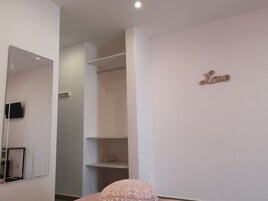Uma casa de banho moderna com um espelho grande, um porta-toalhas e uma estante com um objeto decorativo.