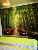 Quarto com um papel de parede de tema florestal, uma cama com colcha verde vibrante e uma cadeira de madeira.