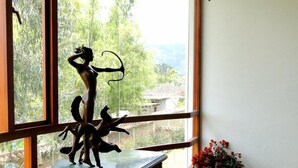 Quarto com armário de madeira, bancada de mármore, escultura em bronze, planta em vaso com flores vermelhas e um candelabro.