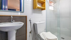 Casa de banho com lavatório, sanita e cabine de duche em vidro.