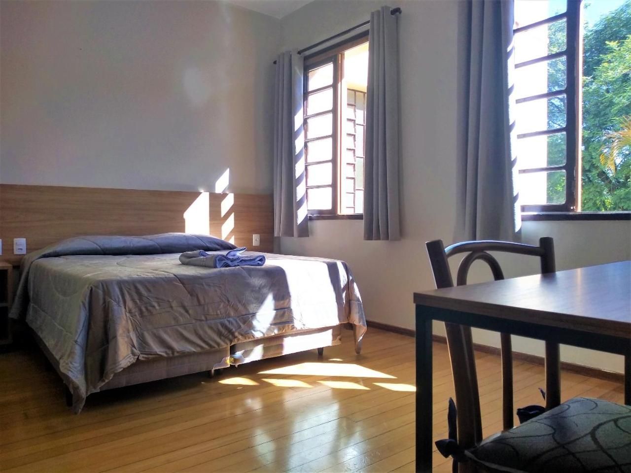 Quarto com cama, mesa e janela com cortinas.