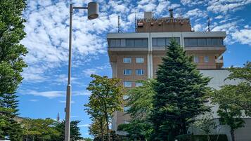 Um edifício de vários andares com telhado plano, rodeado por árvores e um poste de luz.