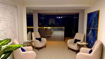 Um lounge moderno com assentos confortáveis, um balcão de recepção e uma grande pintura abstrata.