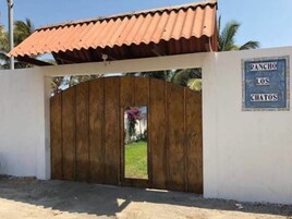 Uma entrada gradeada com uma placa que diz 'RANCHO LOS CHATOS'.